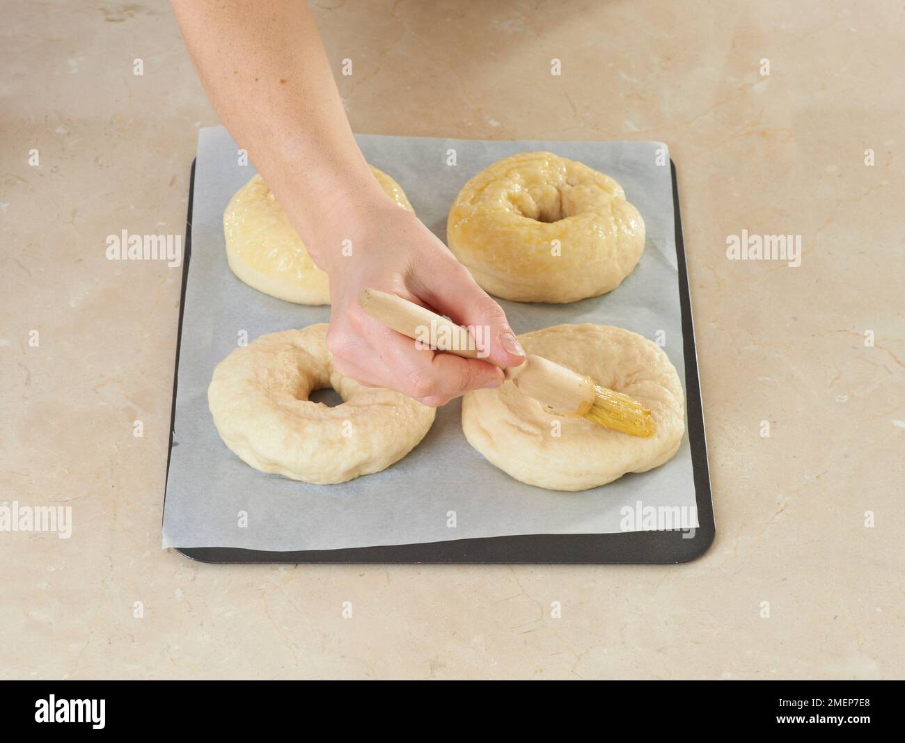 Glazing bagels on baking tray with basting brush Stock Photo - Alamy