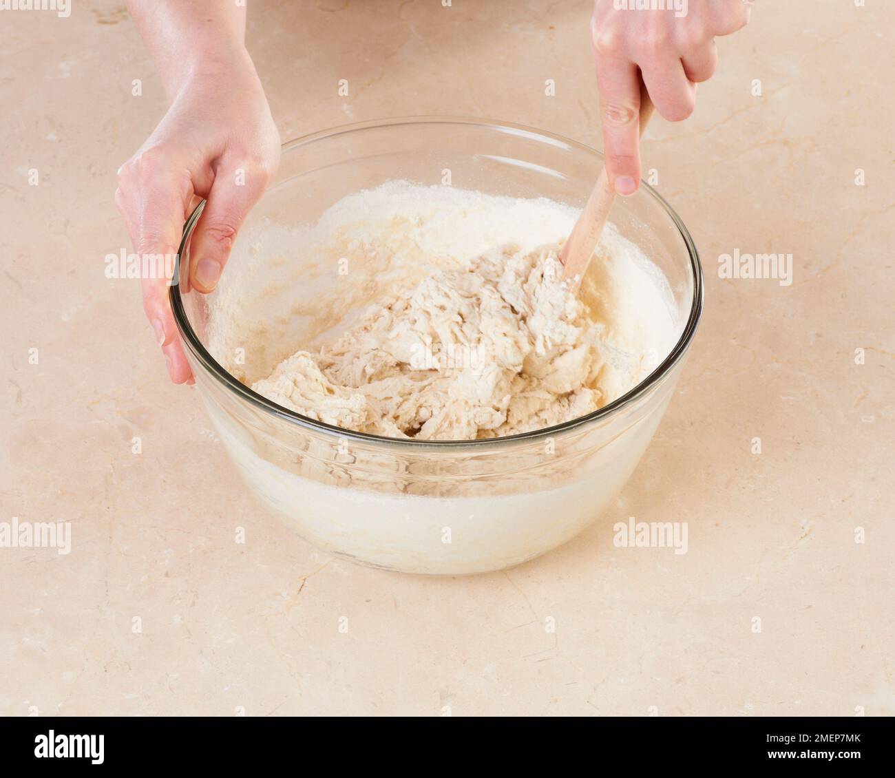 Using wooden spoon to stir Pretzel ingredients in glass mixing bowl ...