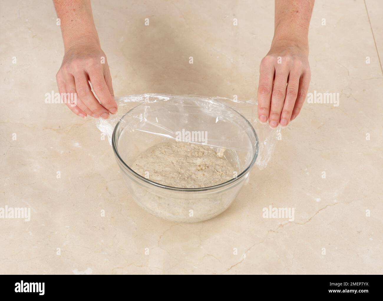 Covering baguette ingredient in glass mixing bowl with cling wrap Stock ...