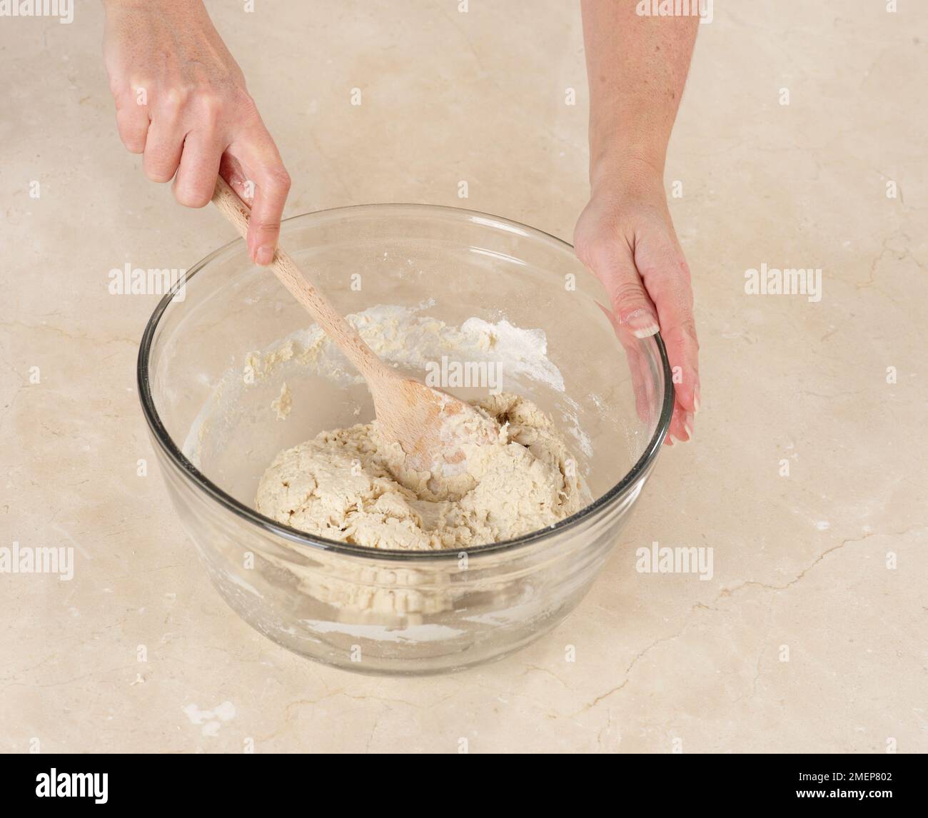 Using wooden spoon to stir in yeast and flour in Stock Photo - Alamy