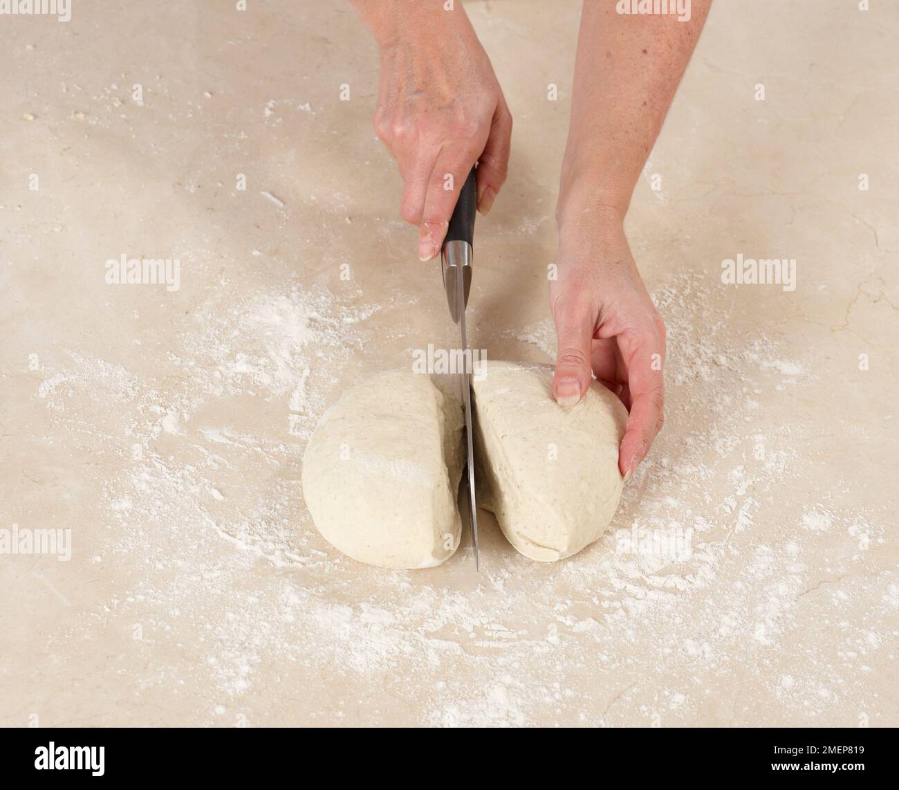 Using large kitchen knife to cut baguette dough in half Stock Photo - Alamy