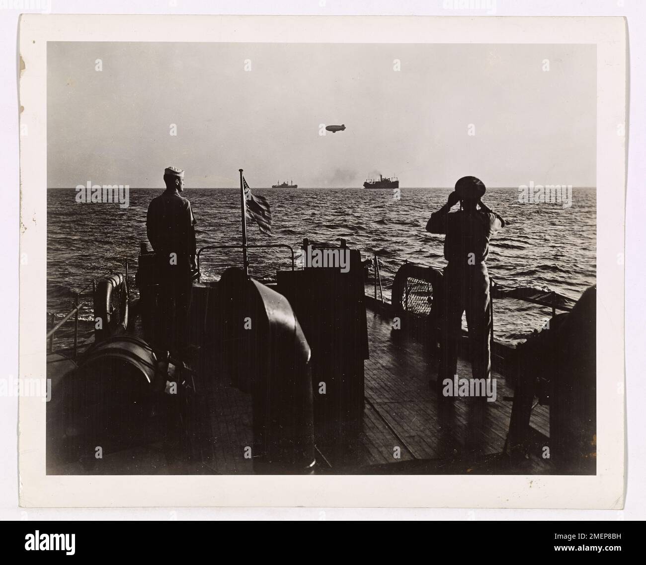 Coast Guardsmen are shown observing incoming ships and a Navy blimp ...