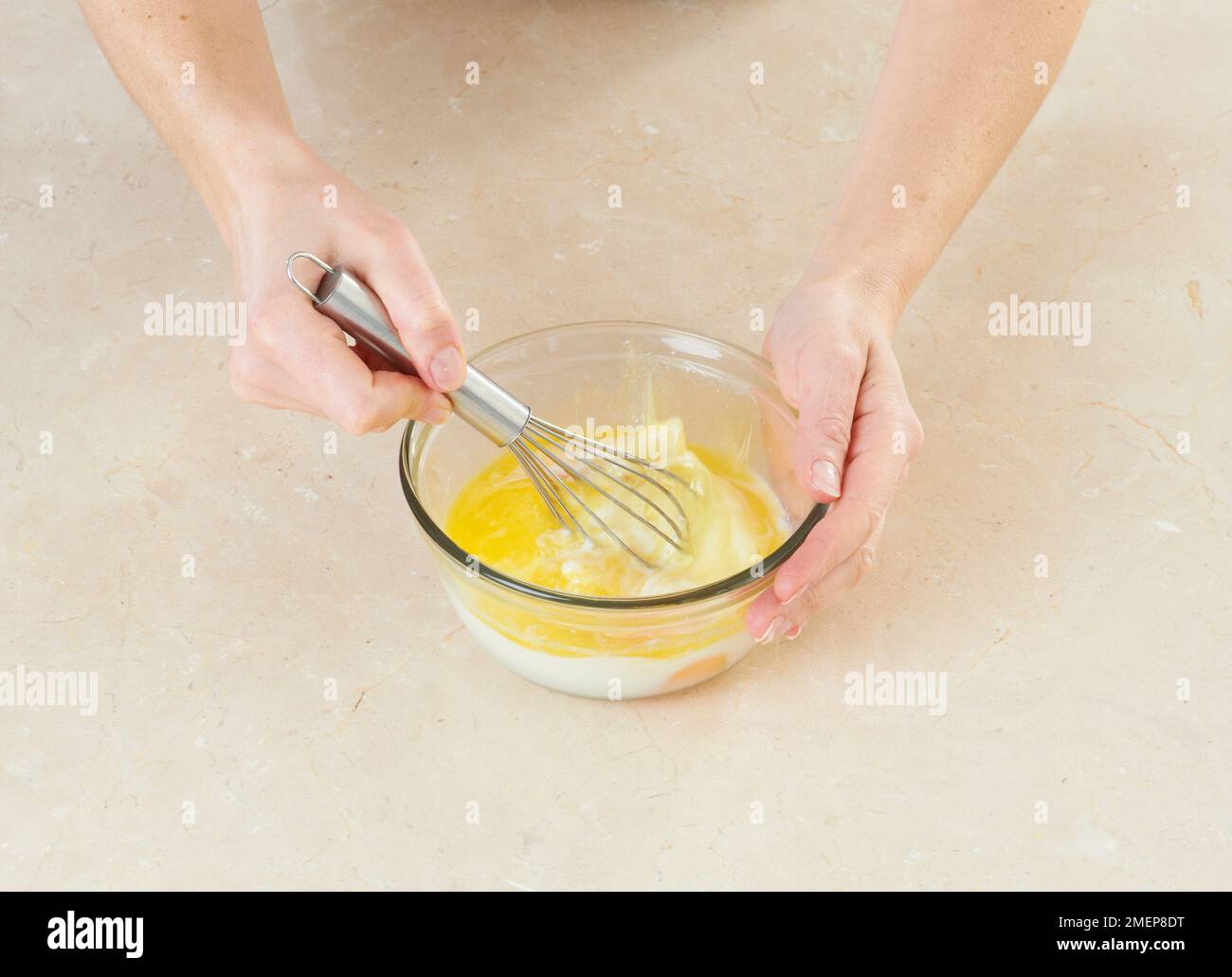 Using wire whisk to mix cornbread ingredients in glass mixing bowl on ...