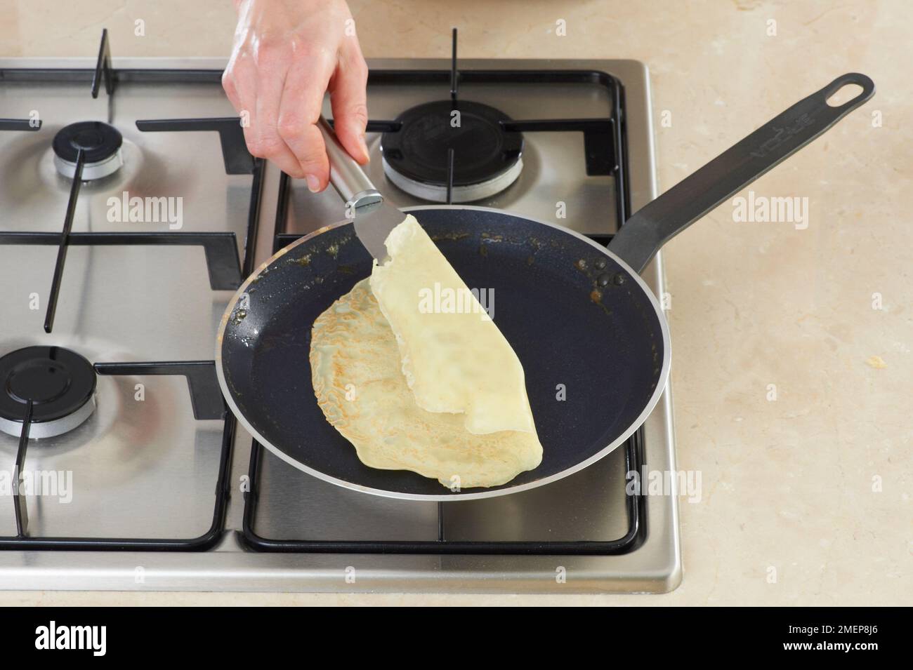 Making crepes, gently loosening crepe in pan with a palette knife Stock ...