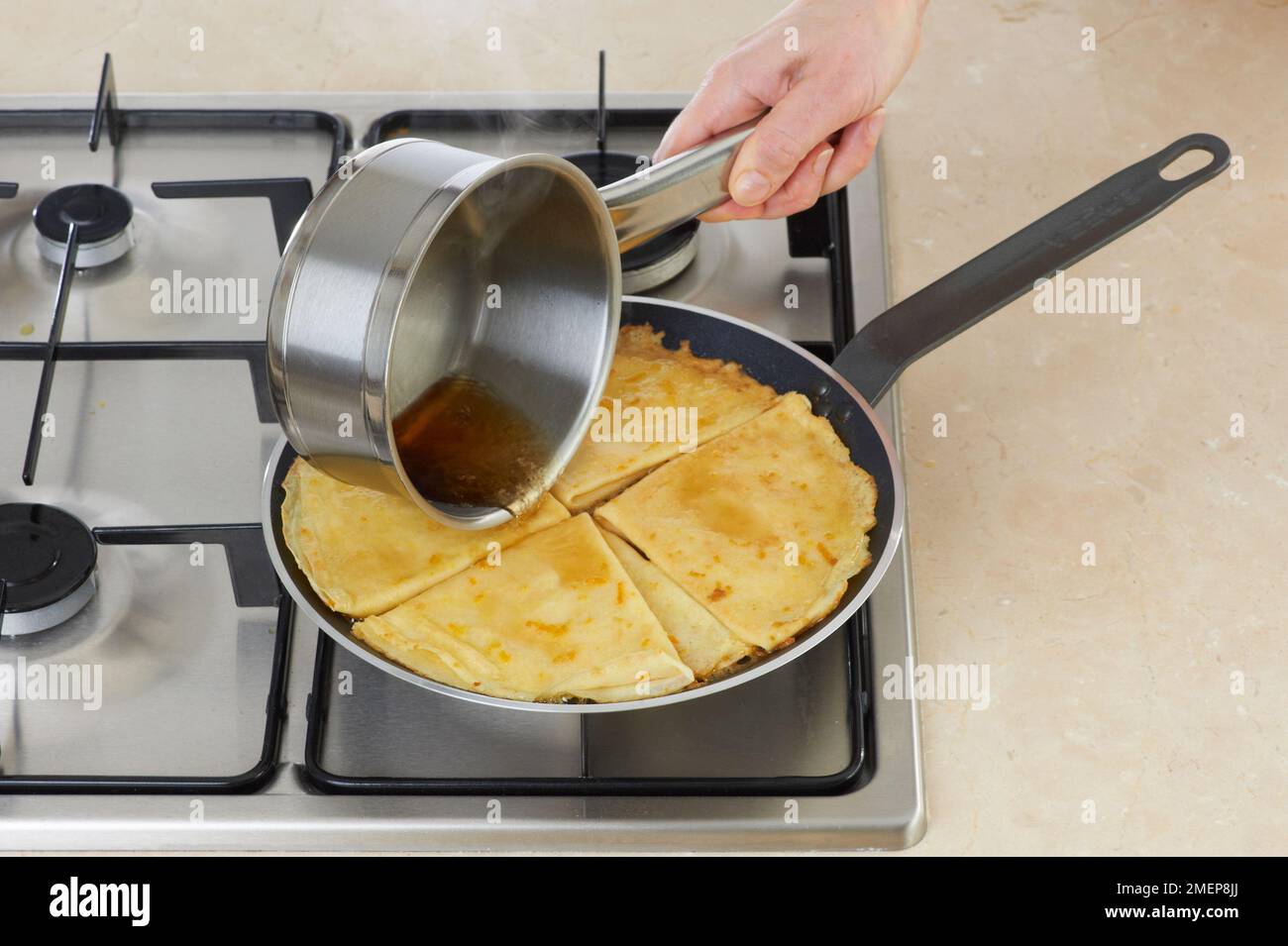 Crepes Suzette, pouring alcohol over folded crepes in pan Stock Photo ...