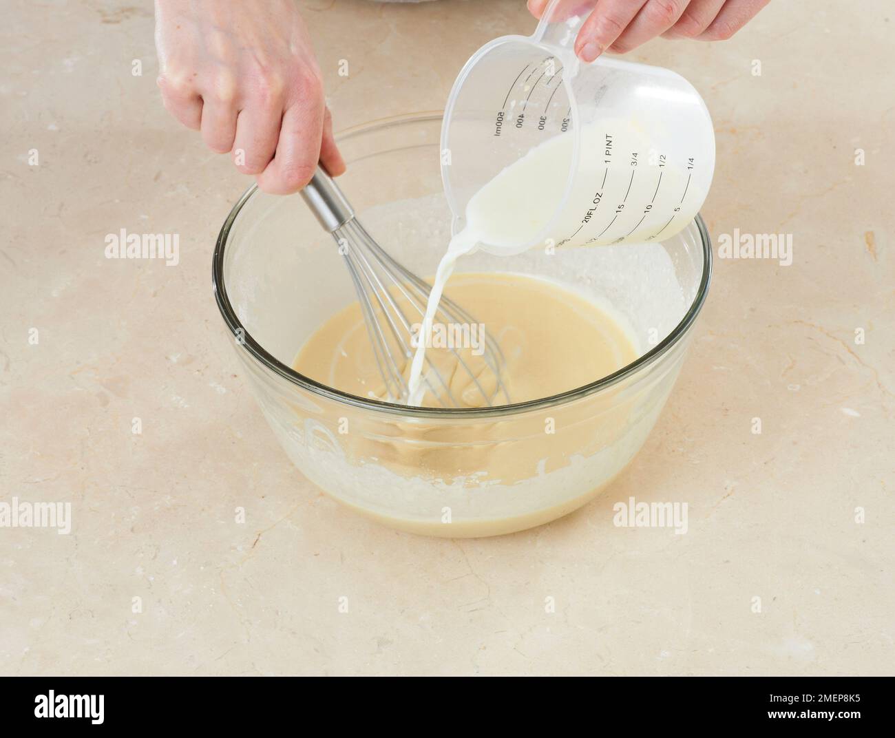 Making Crepes Suzette, pouring milk into batter and whisking Stock ...