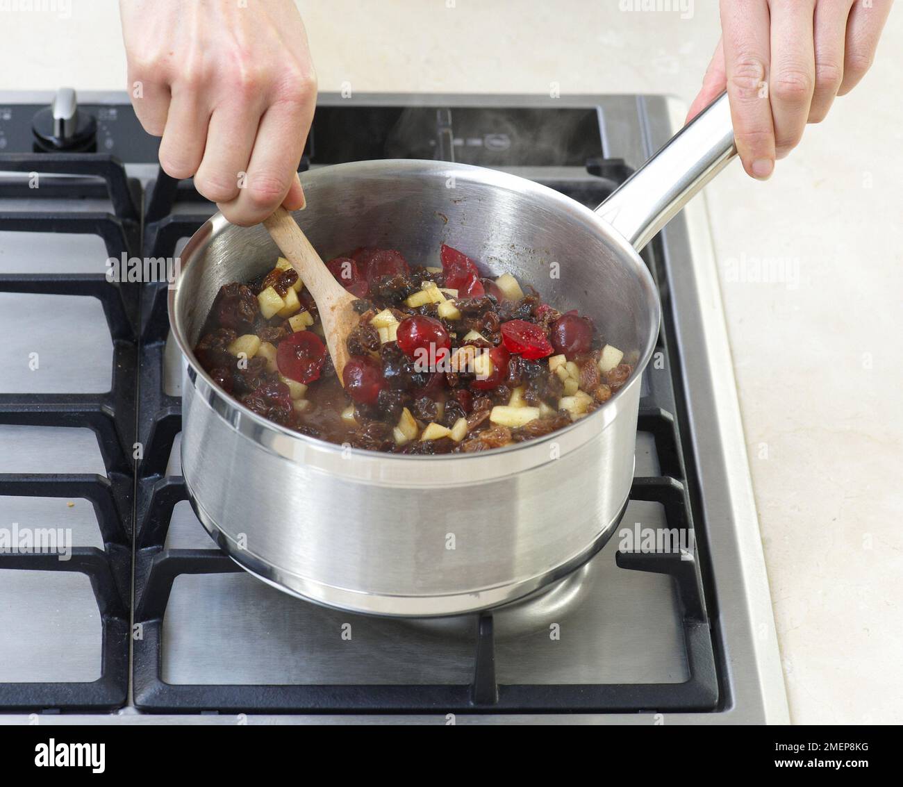 Making Rich Fruit Cake, simmering ingredients in pan over low heat ...
