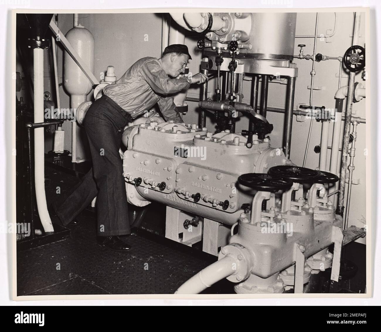A U.S. Maritime Engineer Cadet adjusts a pump in the engine room of a ...