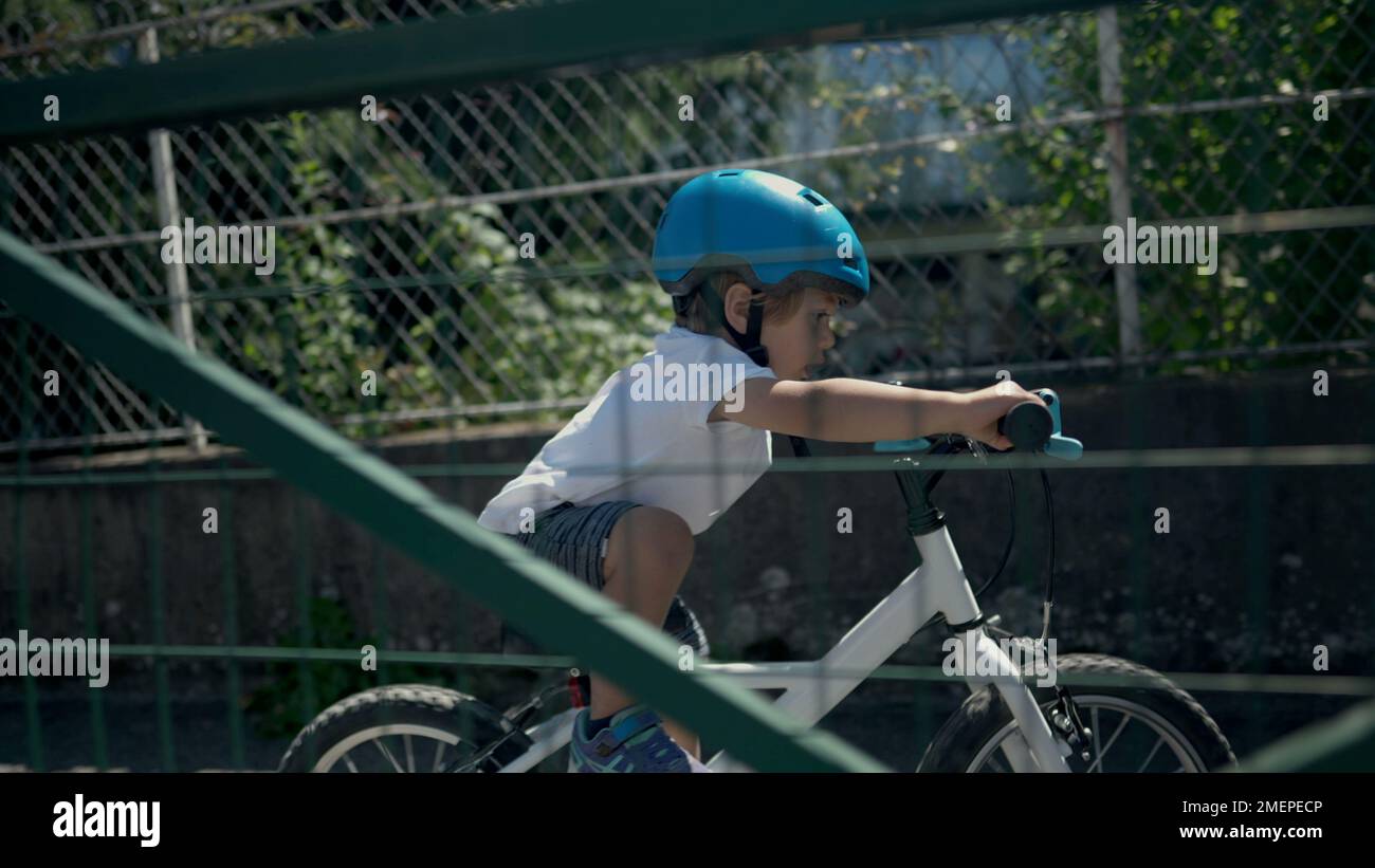 Child riding bicycle outside in urban street little boy rides bike on ...