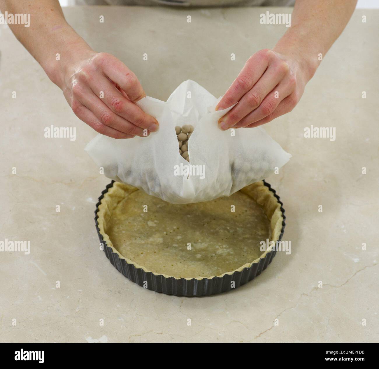 Remove baking beans and paper from pastry base, making a tart Stock ...