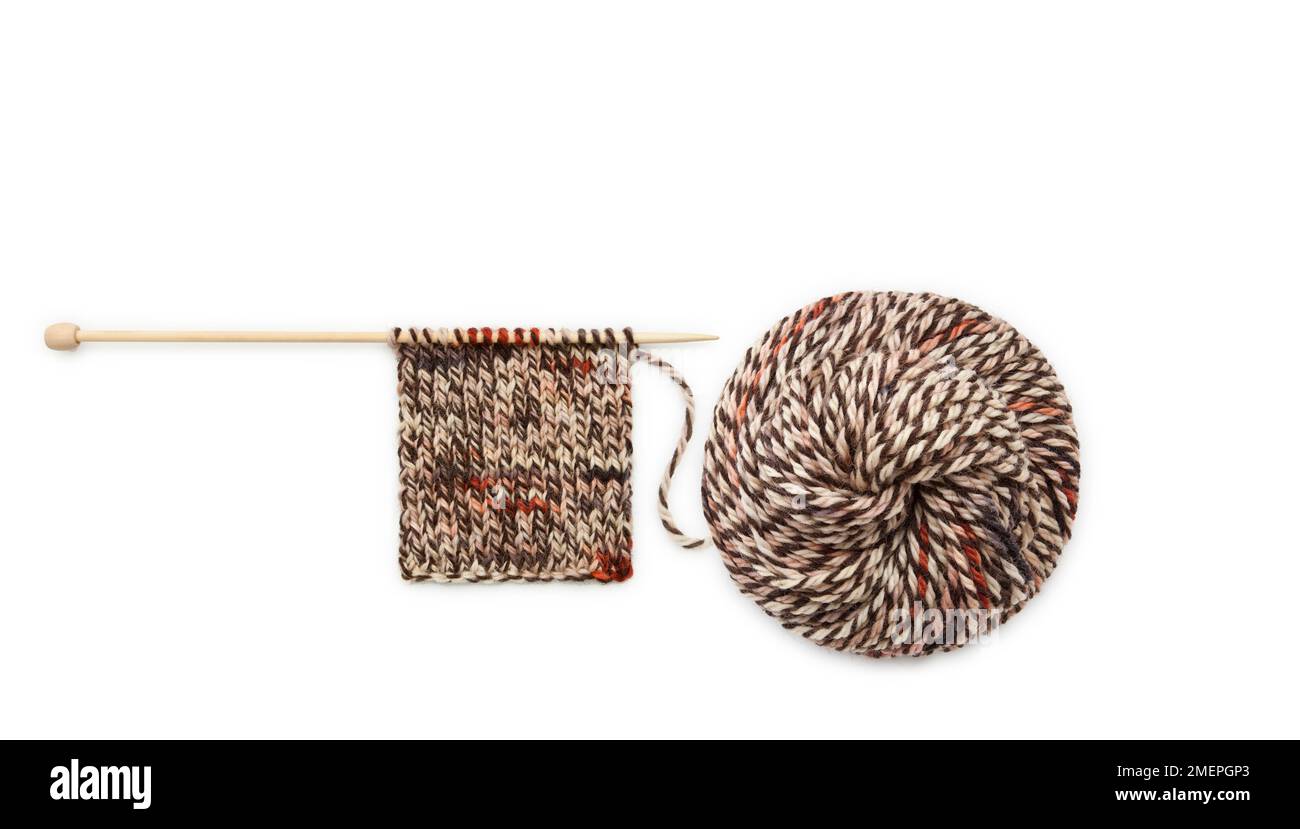Ball of brown and white plied yarn and knitted sample on knitting ...