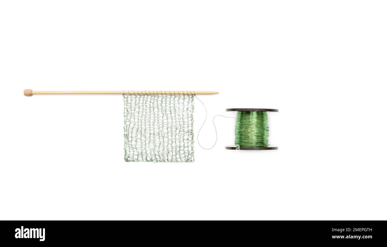 Ball of green wire yarn and knitted sample on knitting needle Stock ...