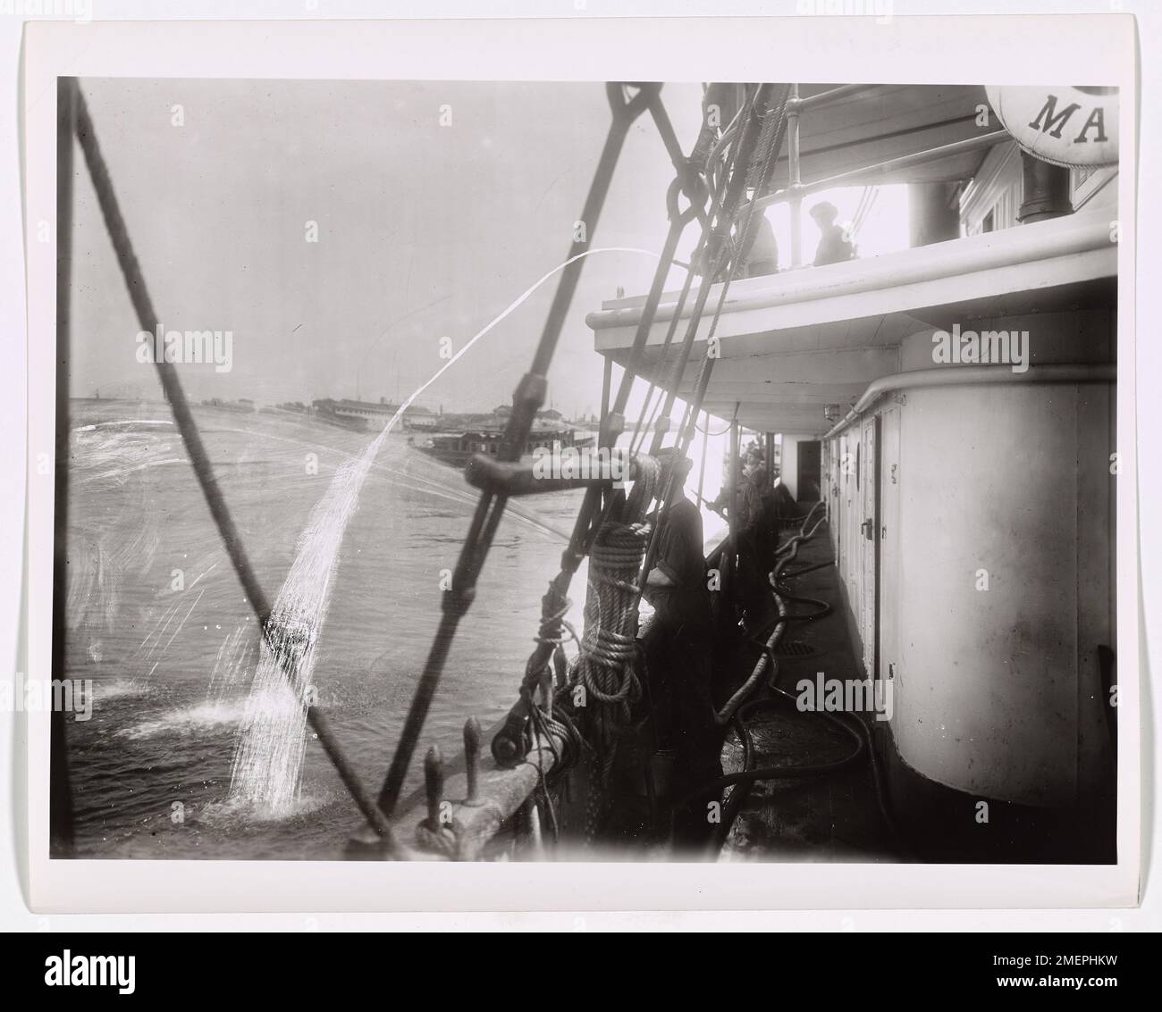 This photograph captures the view from a ship's deck, with crewmen ...