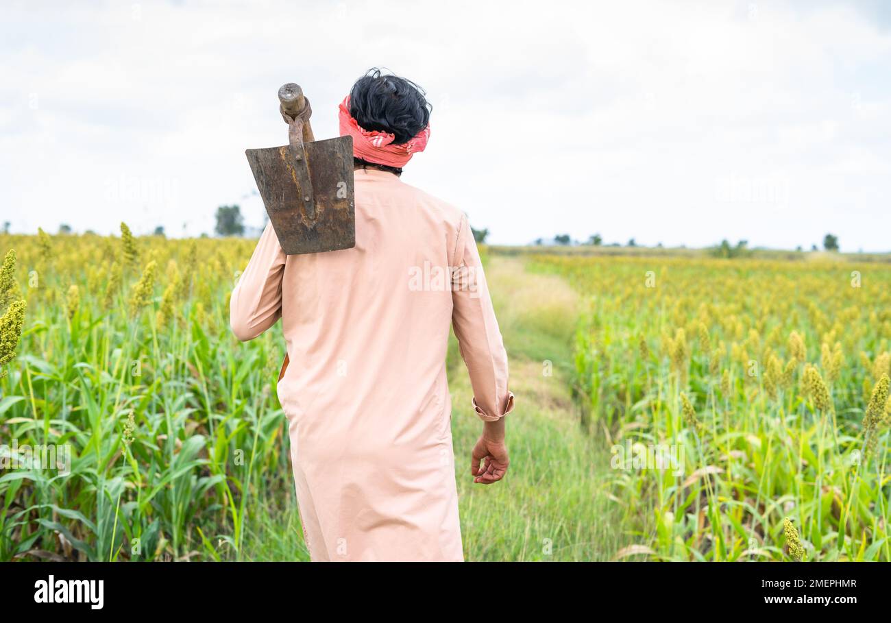 Rear view shot farmer with spade looking around by walking at ...