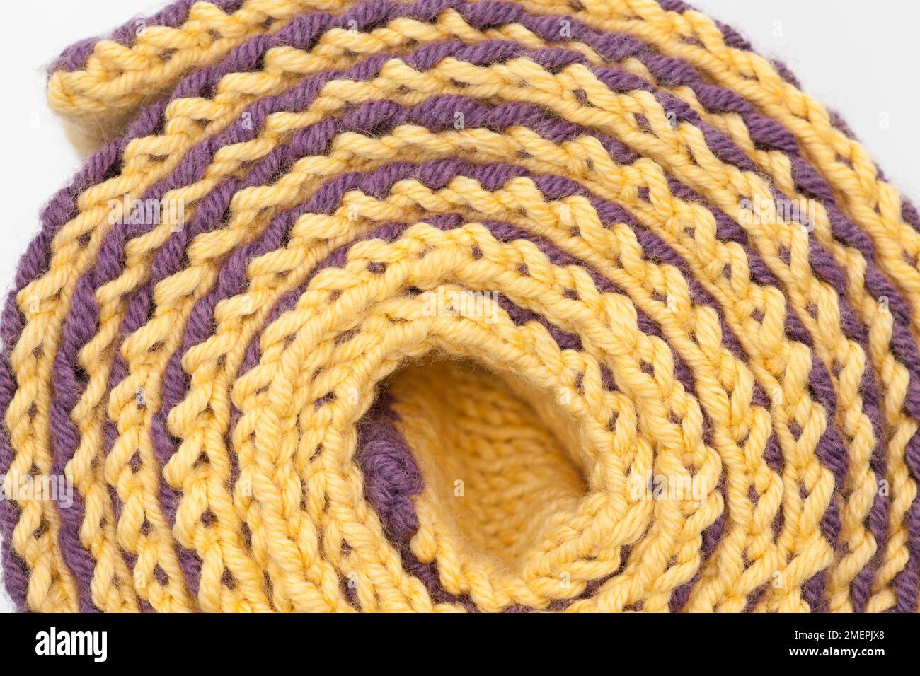 Purple and yellow double stitch knitted wool wound in spiral, close-up ...