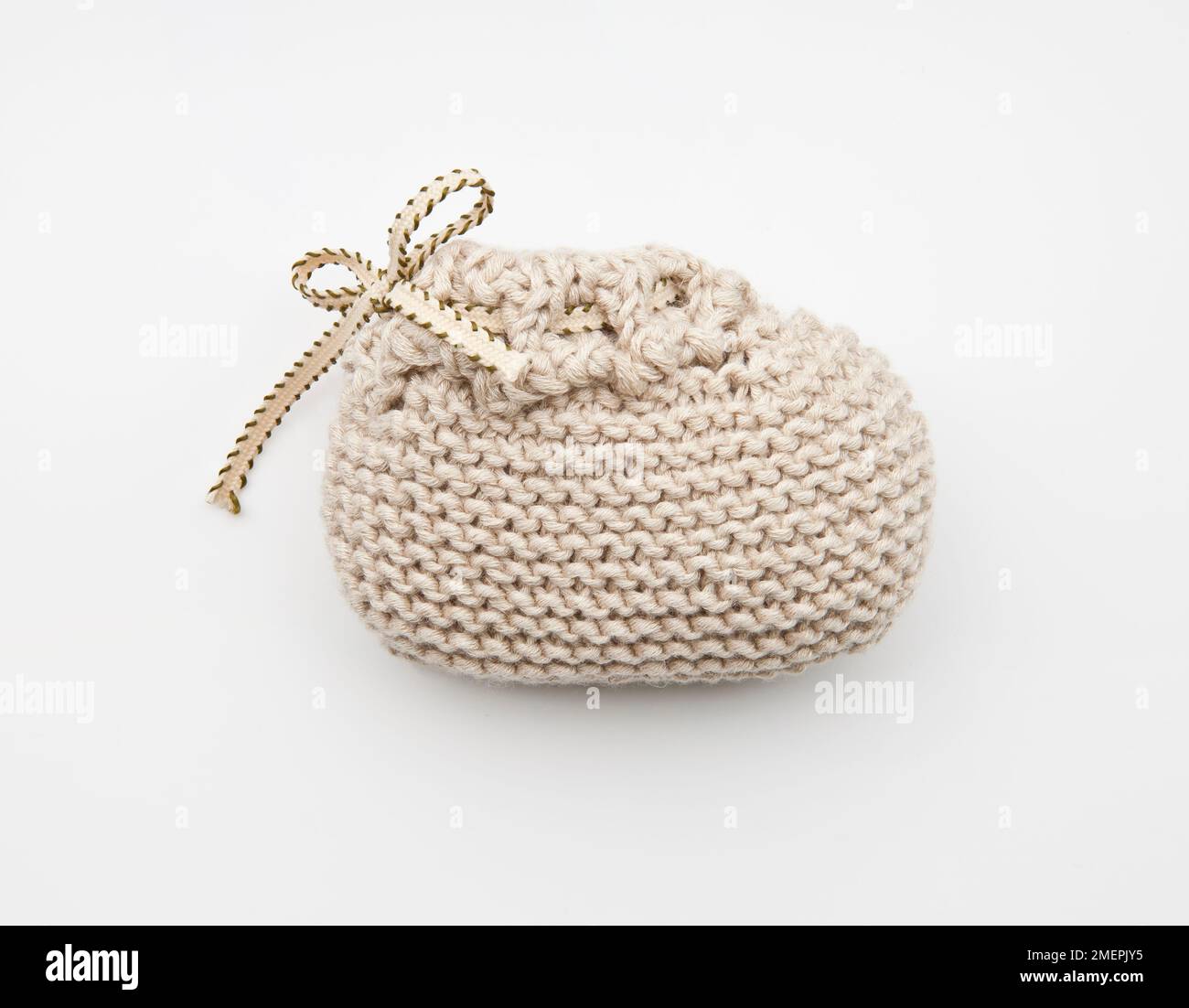 Knitted baby bootie with gold braid bow, side view Stock Photo - Alamy