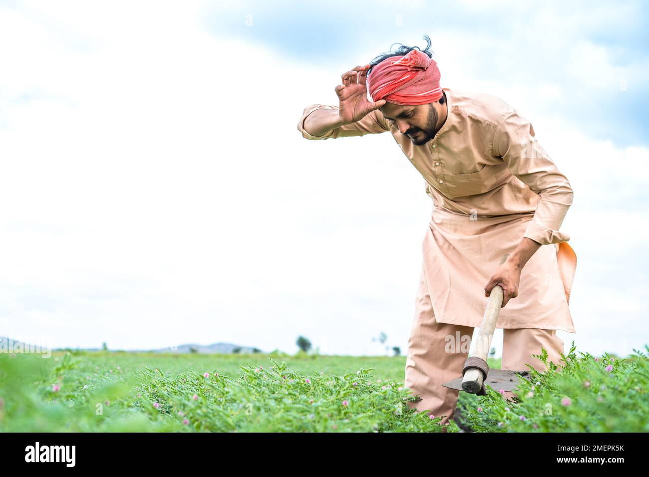 tired young village farmer busy working on farmland during monsoon ...