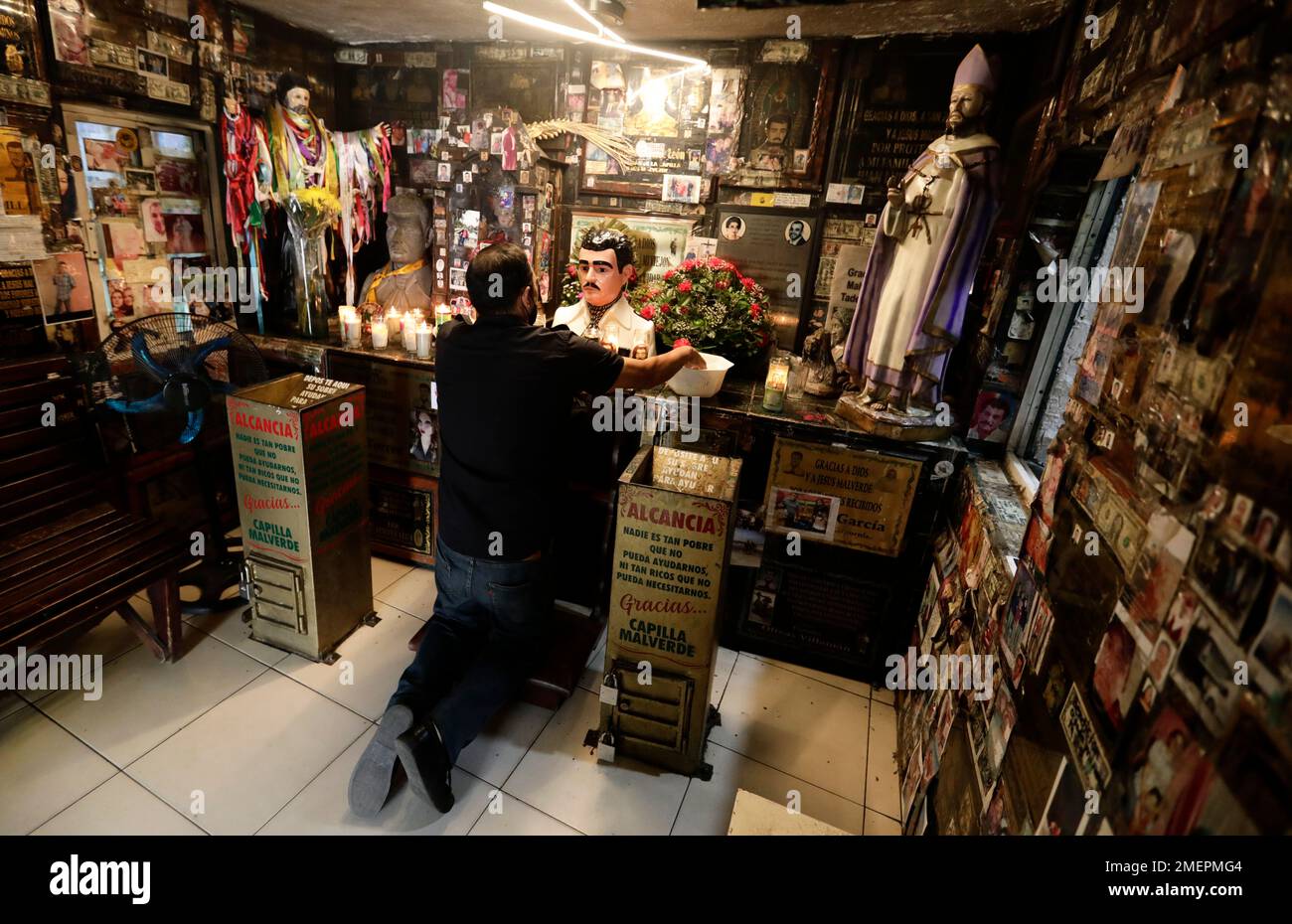 A man prays inside a shrine dedicated to the folk-saint Jesus Malverde ...