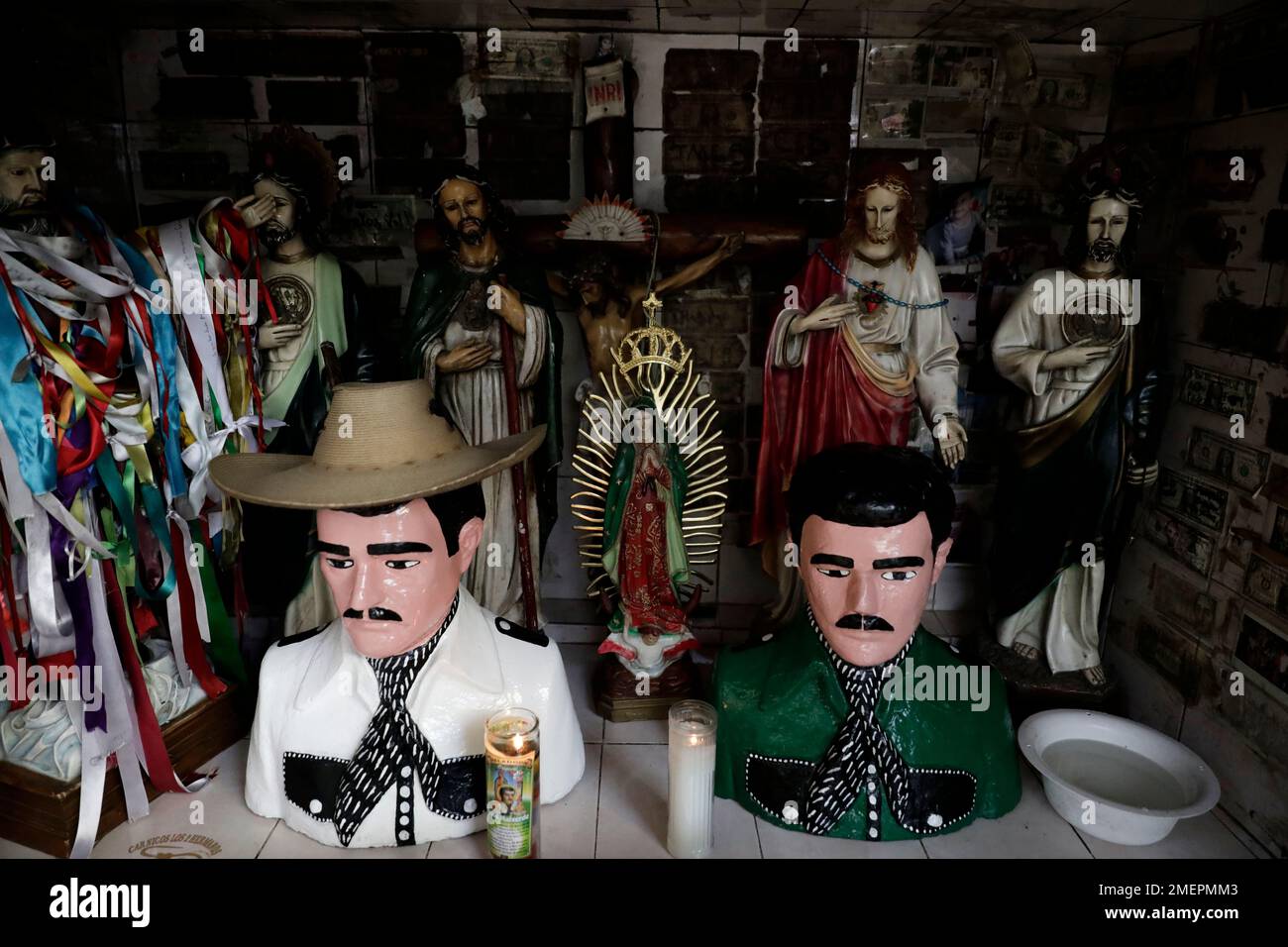Statues of Jesus Malverde sit in front of religious statues inside a ...