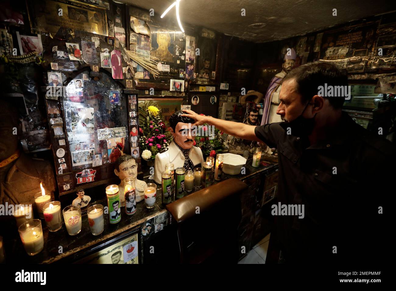 A man touches a statue of Jesus Malverde inside a shrine dedicated to ...