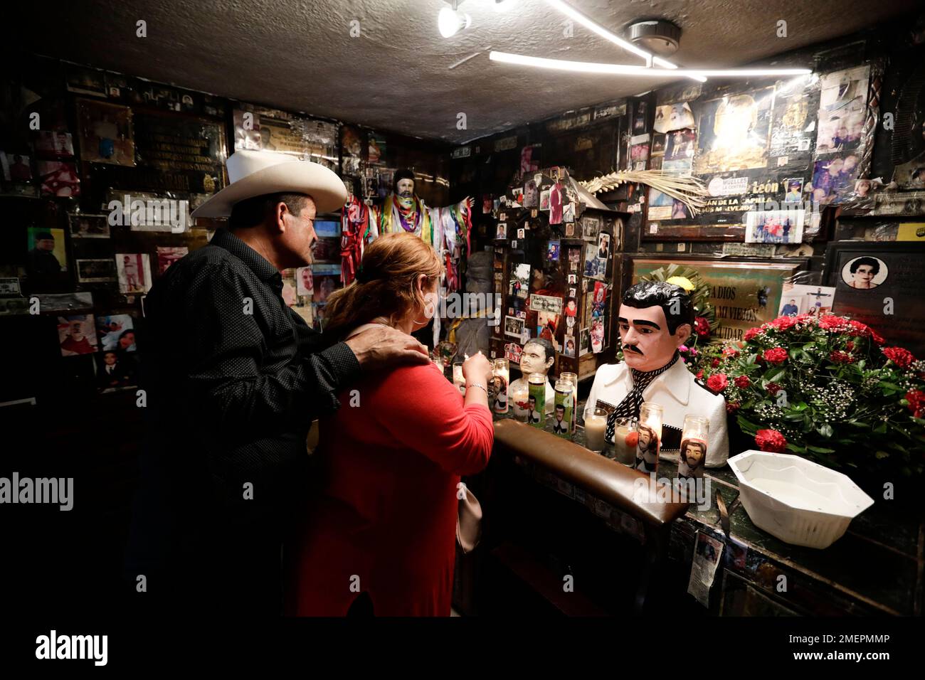 A couple lights a candle inside a shrine dedicated to folk-saint Jesus ...
