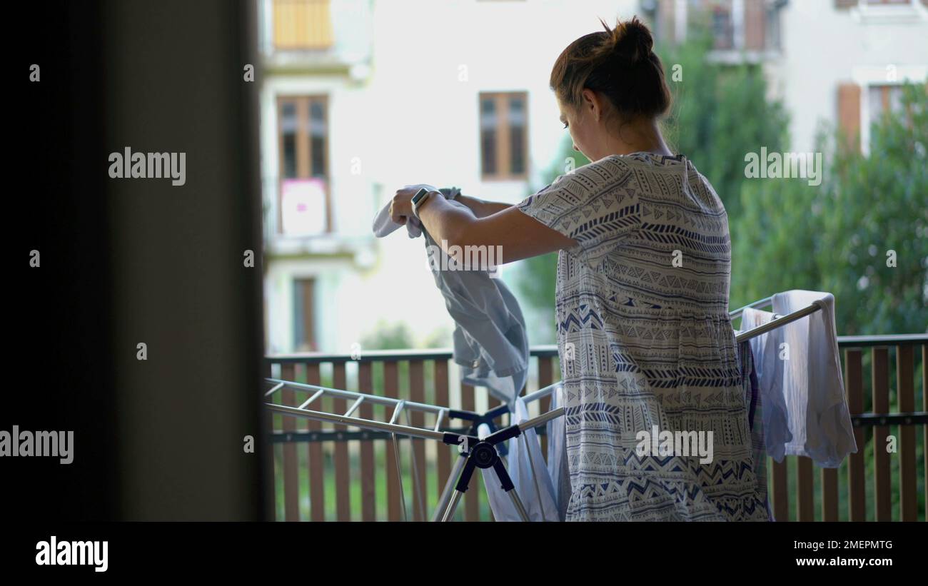 Woman putting clothes to dry outside at apartment balcony Stock Photo ...
