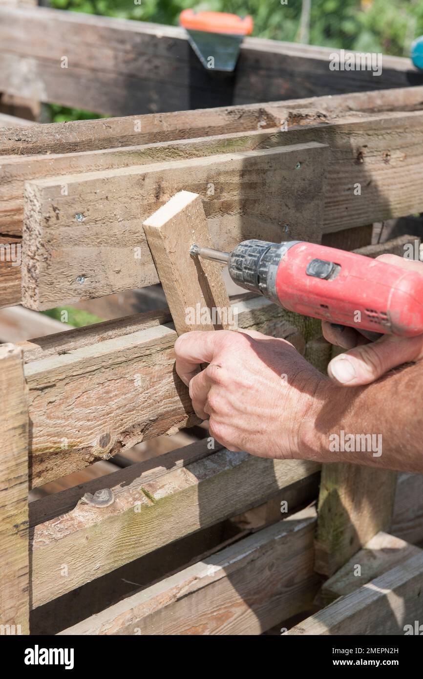 Attaching wood with drill, constructing compost heap Stock Photo - Alamy