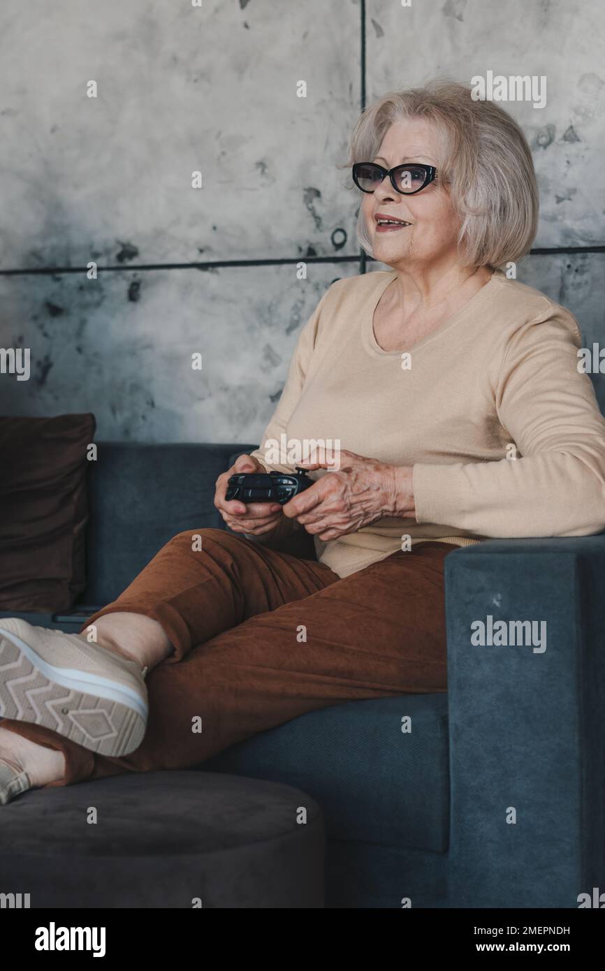 Happy elderly gray haired senior woman, sitting on sofa in living room ...