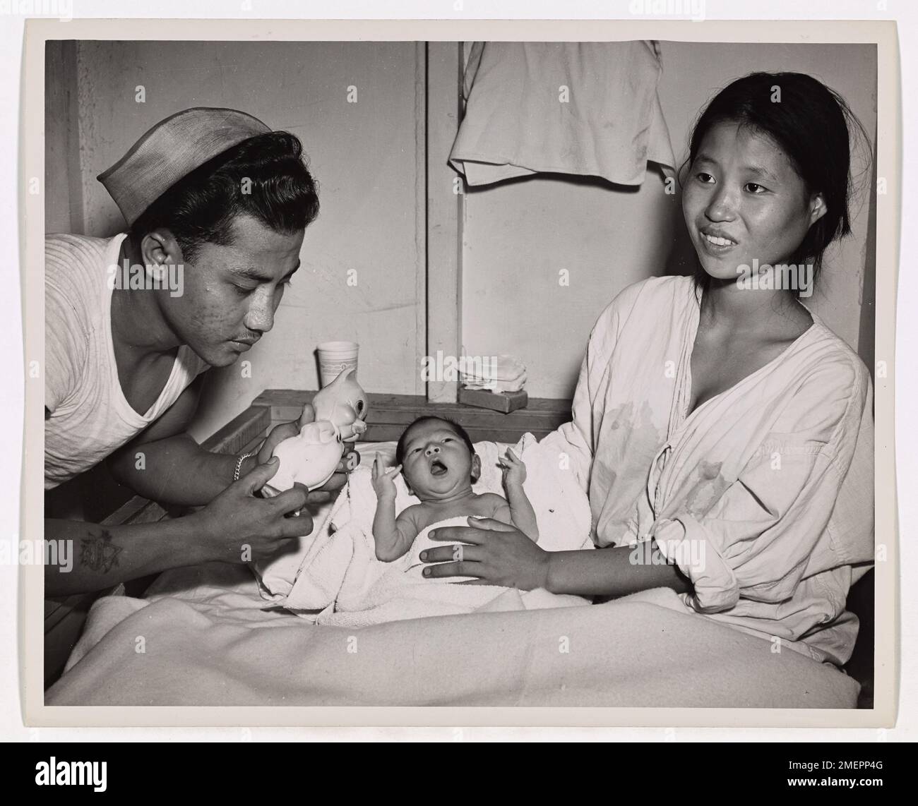 A Coast Guardsman attempts to entertain a Japanese infant with a rubber ...