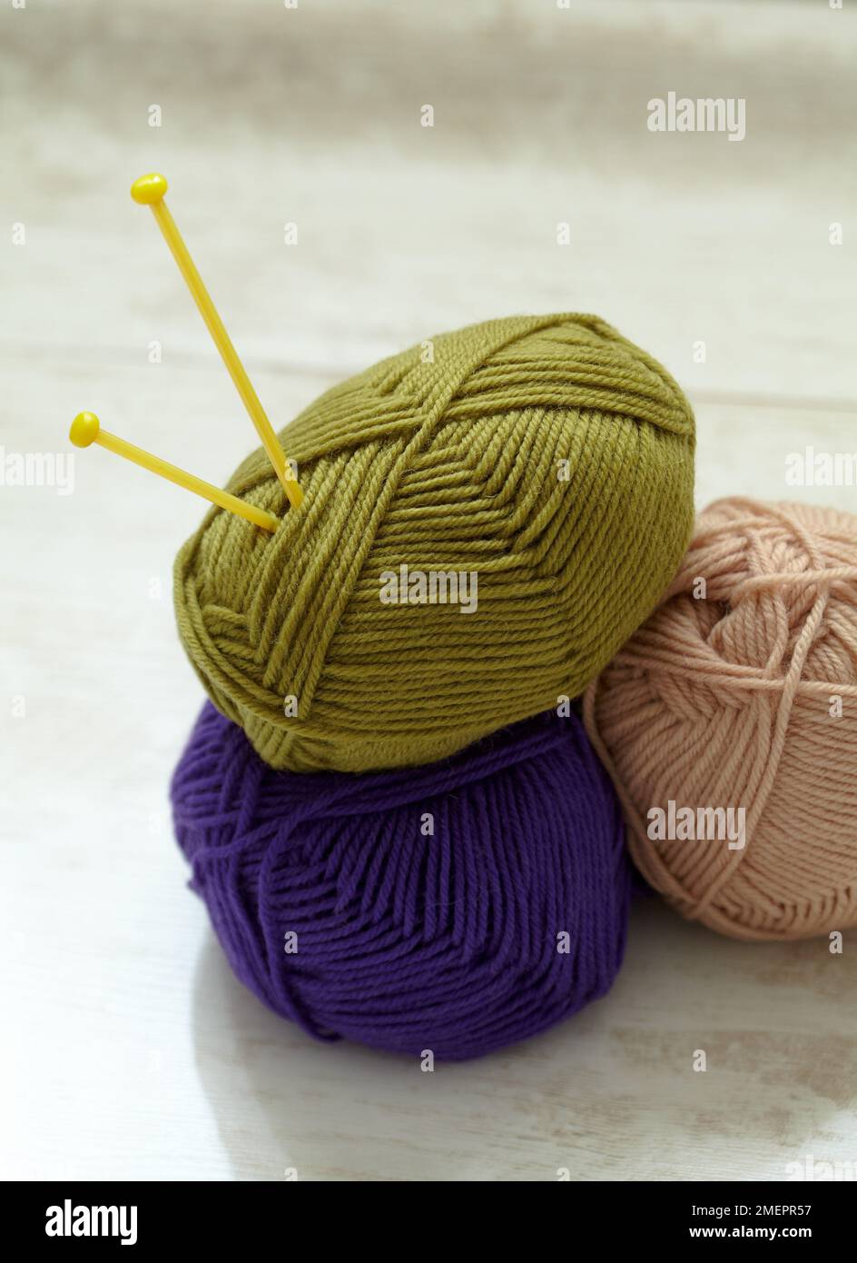 Three balls of wool with knitting needles stuck in one Stock Photo - Alamy