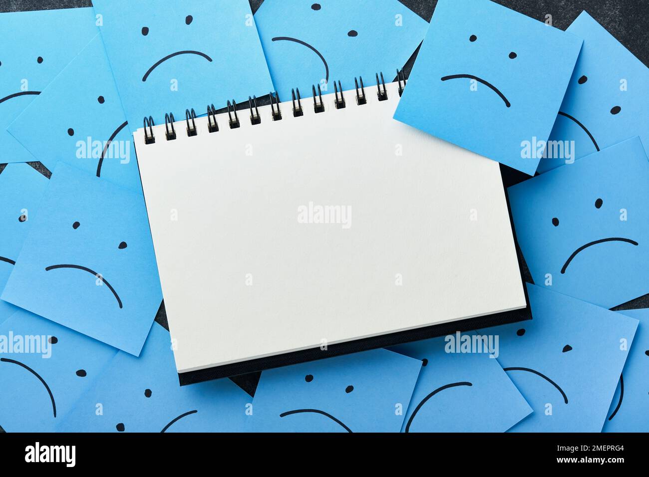 Blue sticky notes blank with drawing sad face on black background with ...