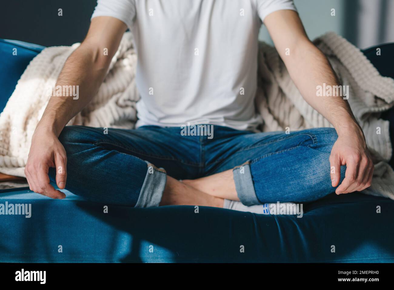 Man meditating, practicing yoga sitting on sofa in lotus pose for ...