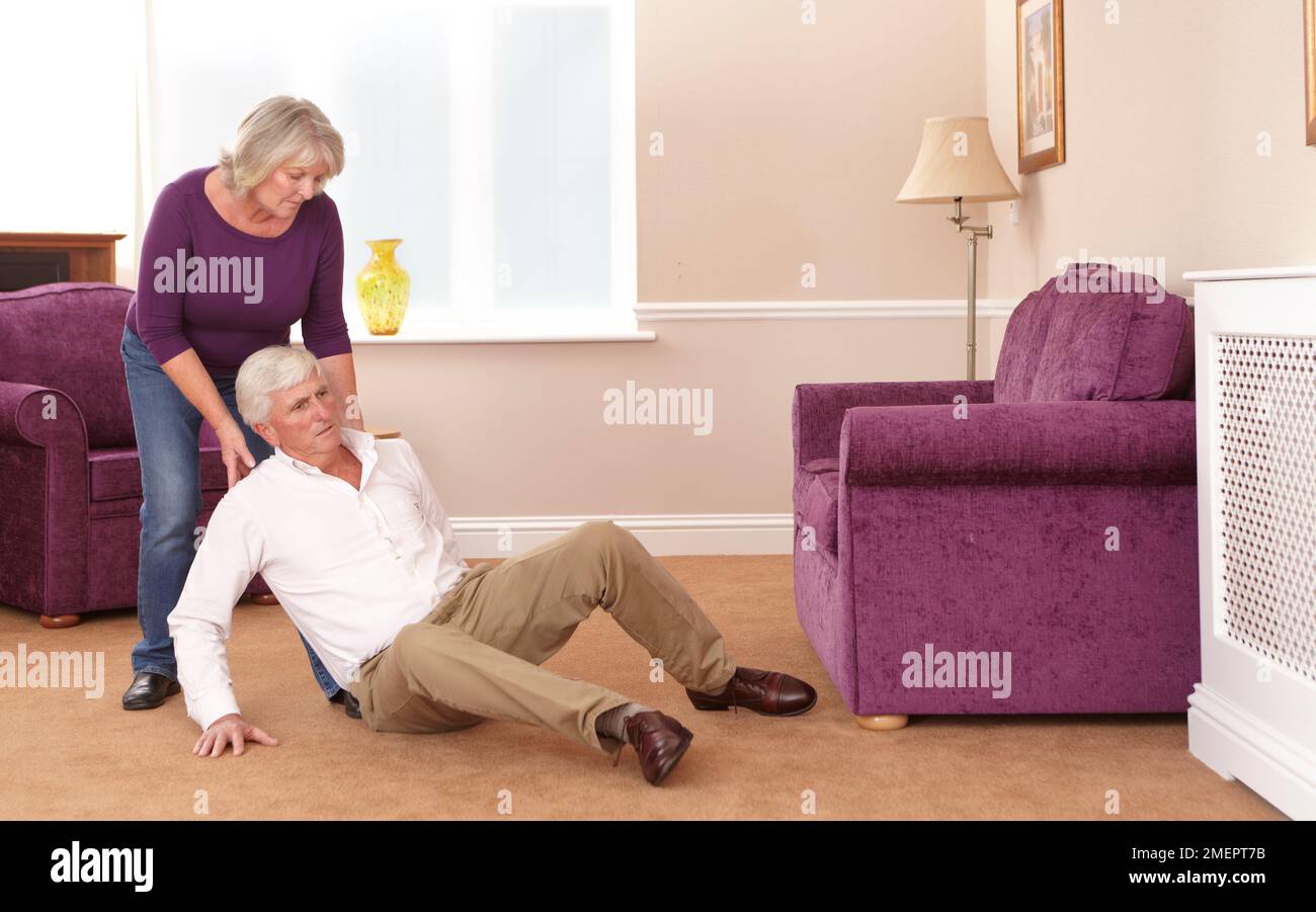 Controlling a fall, man sat on floor at foot of woman's legs after fall ...