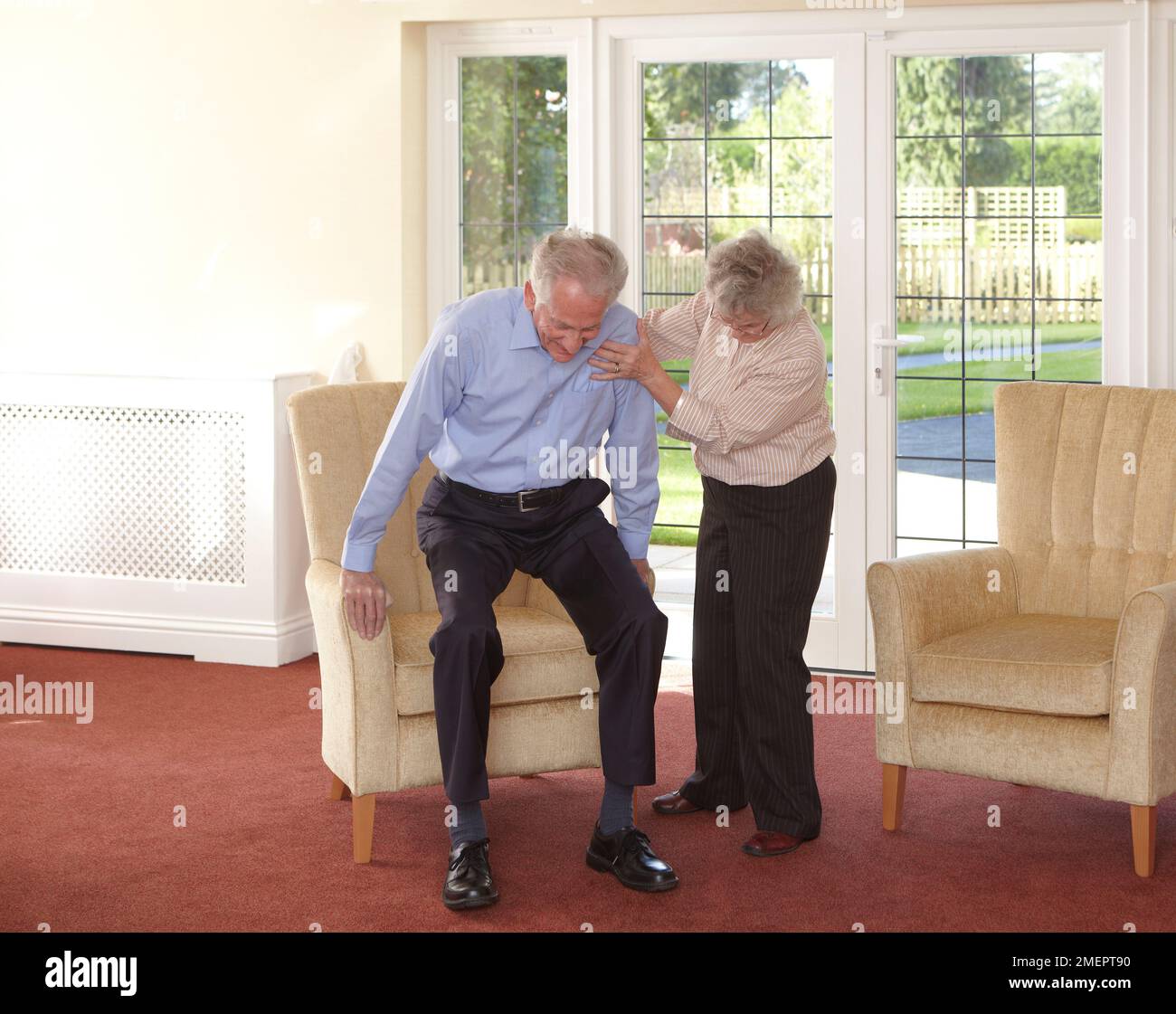 Woman assisting man to get out of an armchair to stand up Stock Photo ...