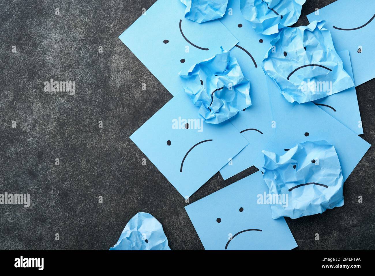 Blue crumpled sticky notes blank with drawing sad face on black ...