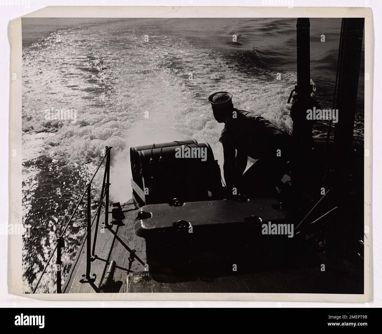 A Coast Guardsman stands ready to deploy ash cans during a mission ...