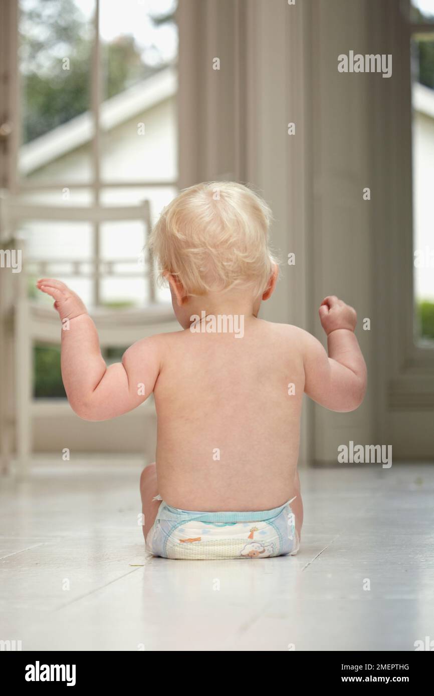 Boy sitting on floor, back facing forward, 1 year 1 month Stock Photo ...