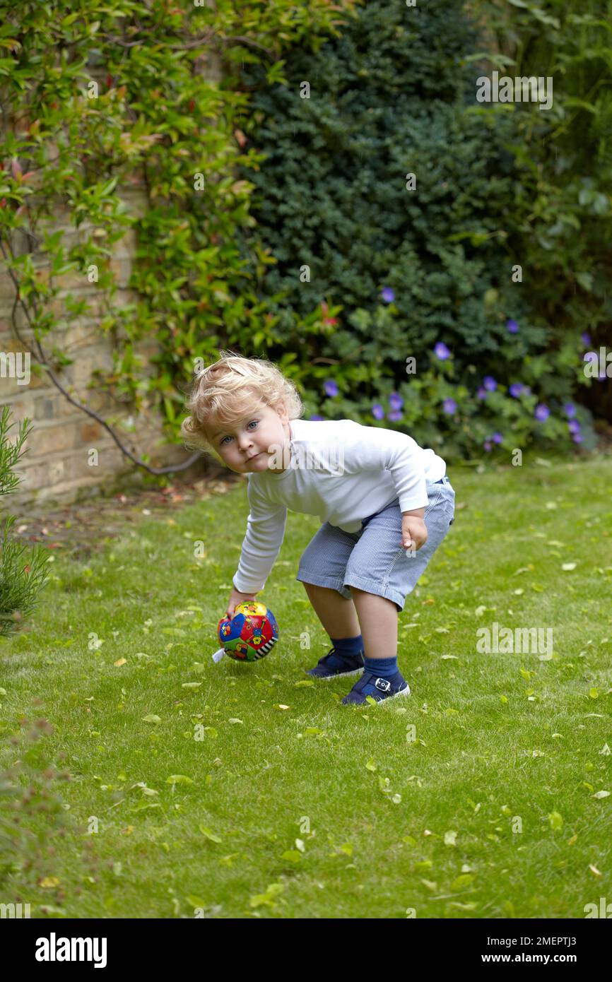 Boy bending to pick up a ball, 2 years 4 months Stock Photo - Alamy