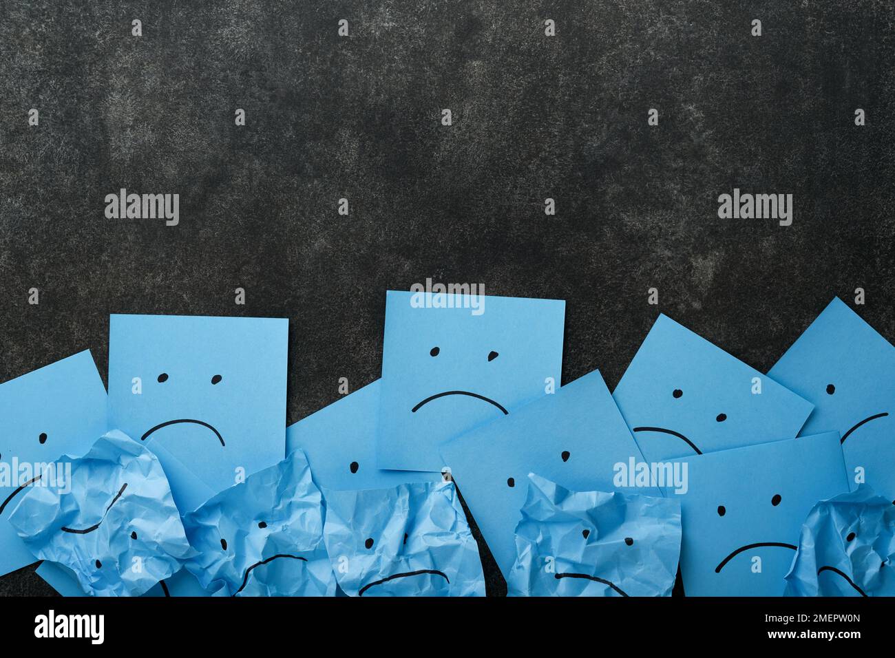Blue crumpled sticky notes blank with drawing sad face on black ...