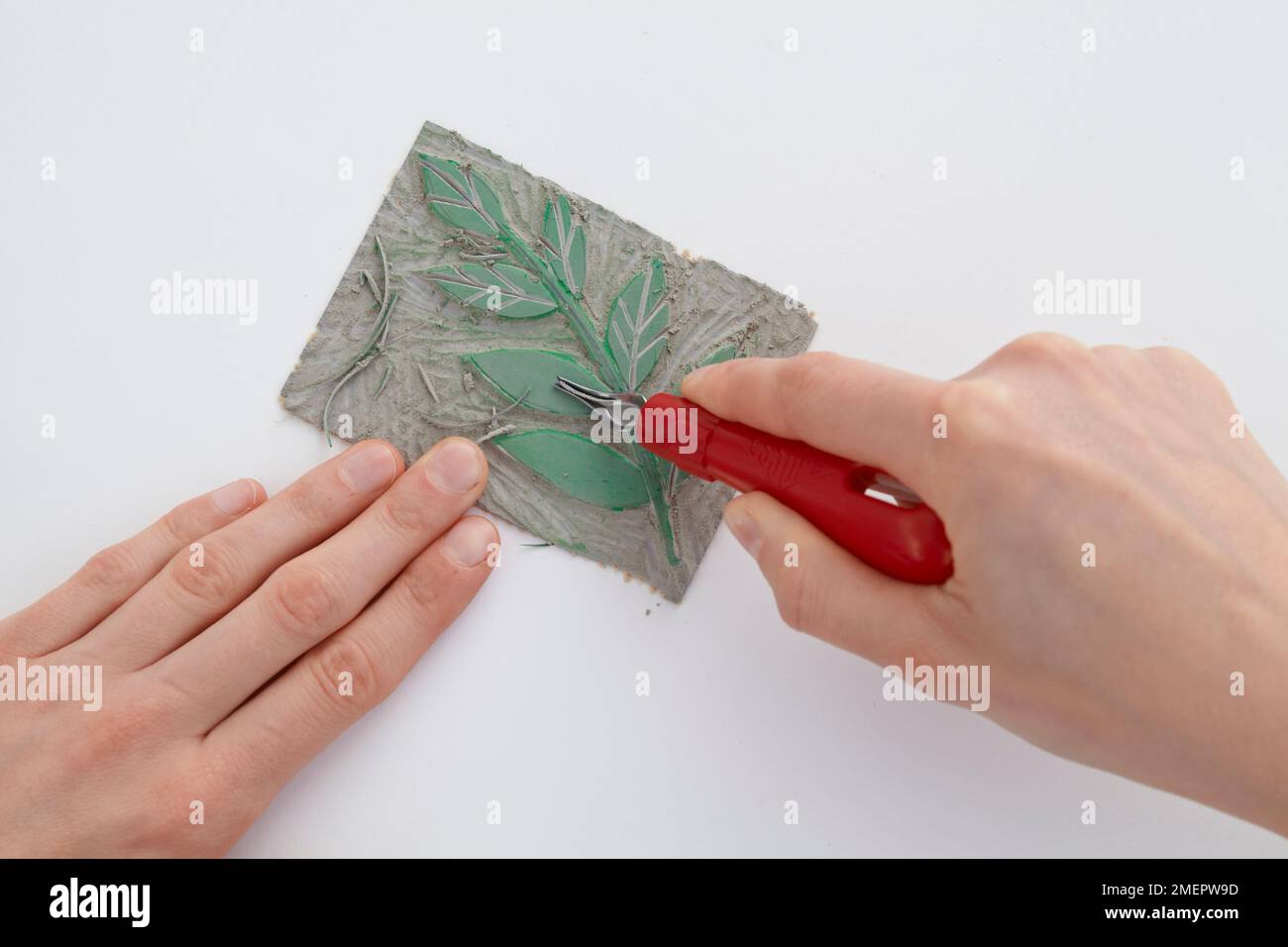 Using V-shaped gouge to cut away more of the design to add second colour to lino print, close-up ...