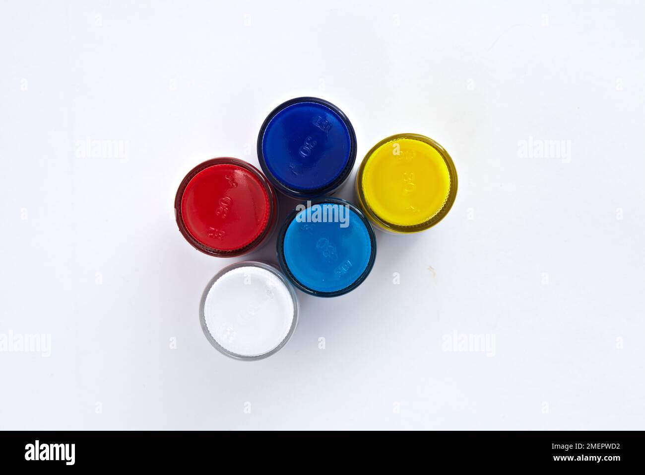 Small glass pots of red, blue, yellow, and white fabric paints, close ...