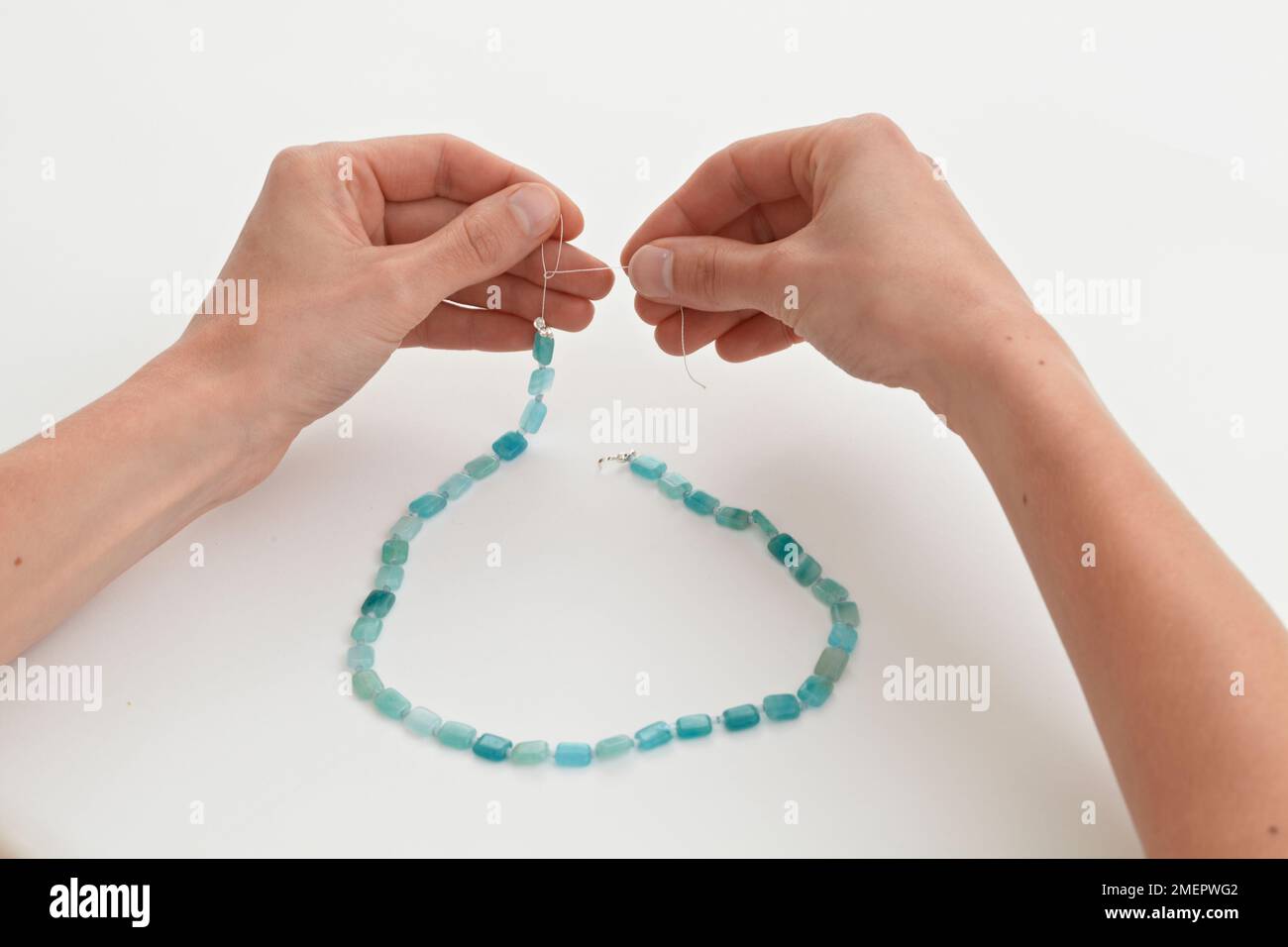 Inserting thread at each end of necklace through hole in calotte to fix ...