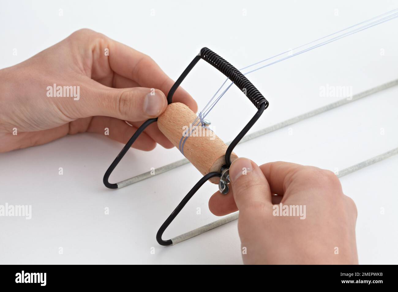 Loom weaving beads, tightening wing nut of roller to take up slack of ...