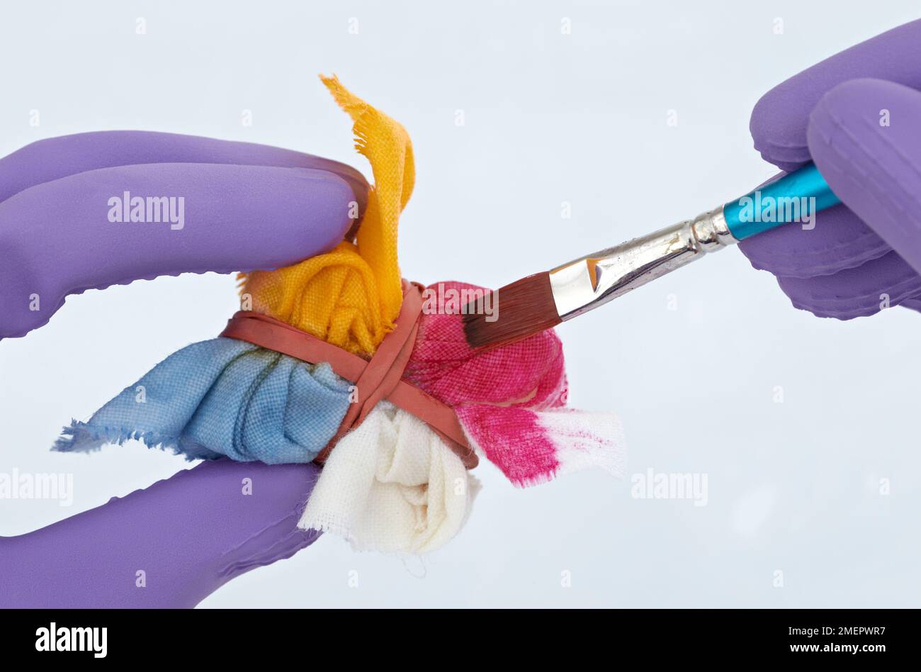 Applying dye to fabric using paintbrush to create a multicoloured tie ...