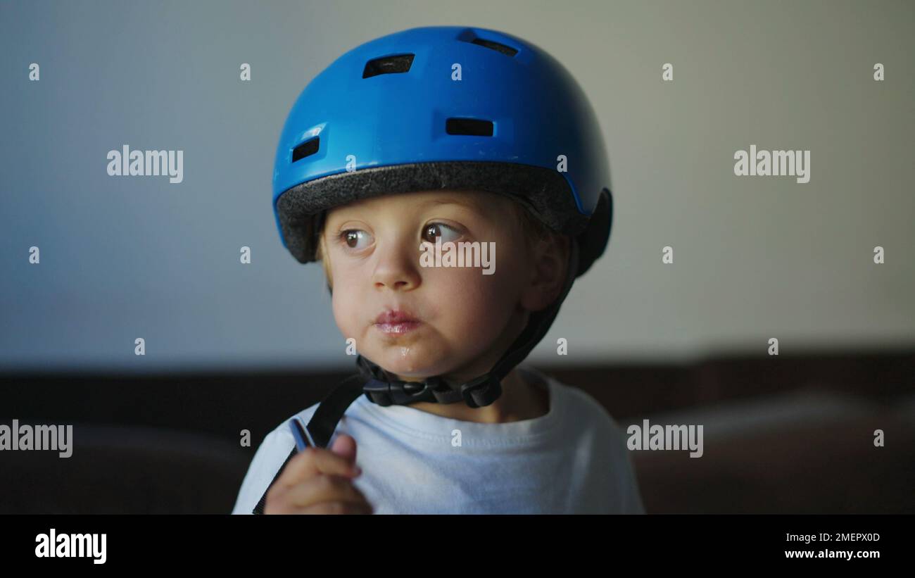 Pensive little boy chewing food wearing protective helmet Stock Photo ...
