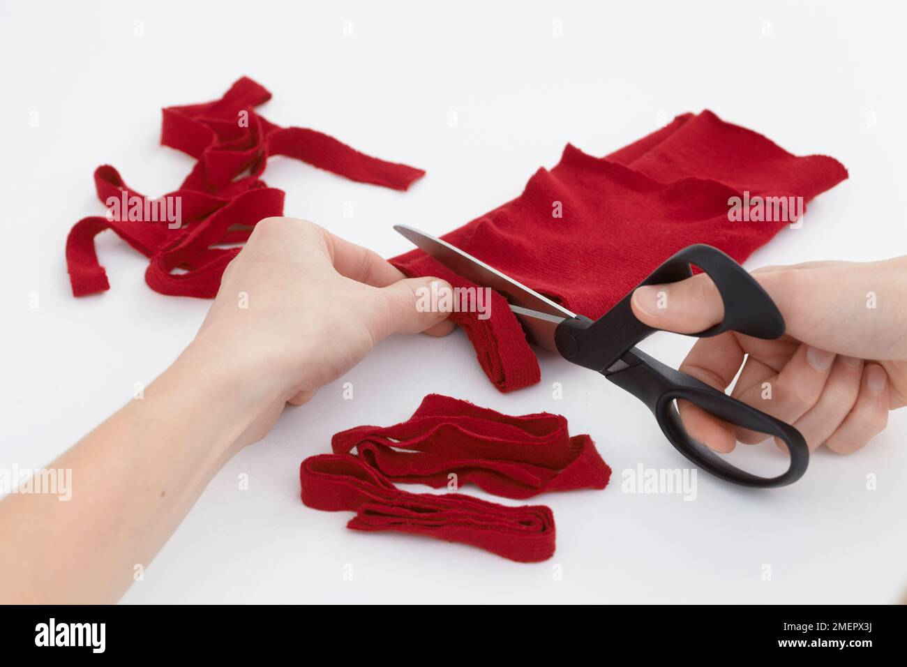 Using scissors to cut folded strips of fabric to make rag rug using ...