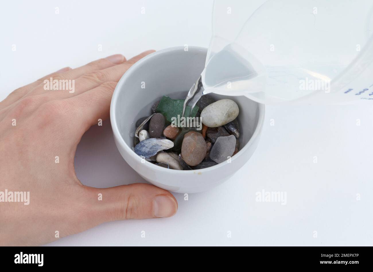 Pouring boiled water over shells and stones in bowl to sterilize, close ...