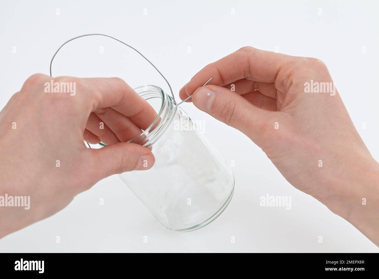 Woman hanging jar, pulling free end of wire over to form handle, close ...