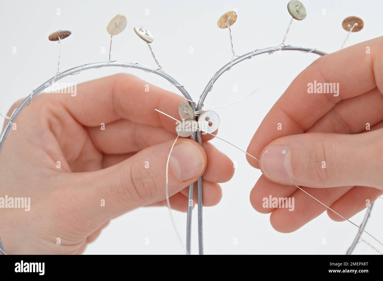 Attaching buttons to wire heart shape decoration using fine wire, close ...