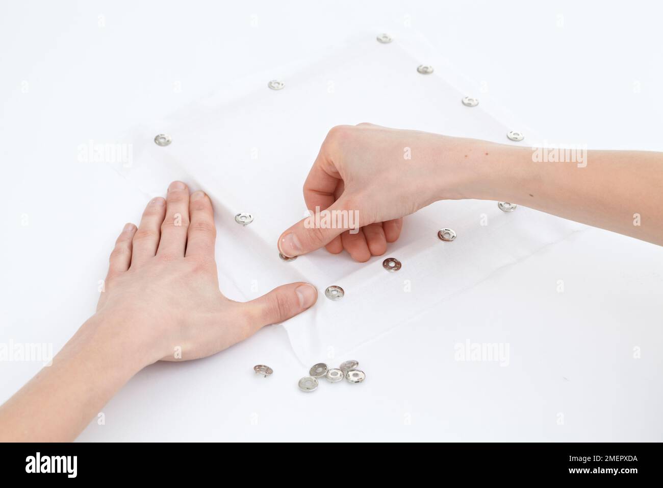 Woman pressing spring press stud buttons on batik frame, close-up Stock ...